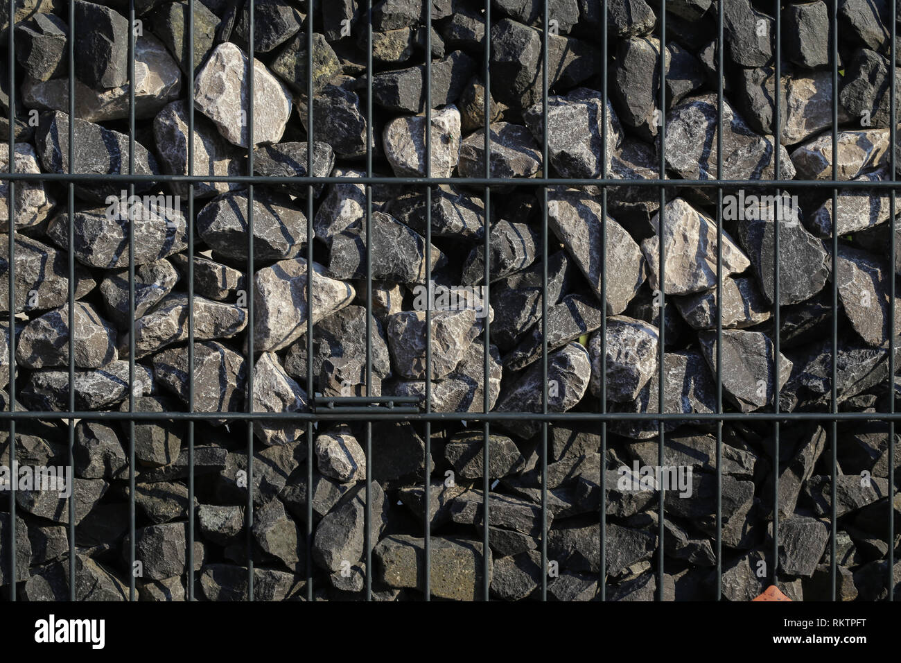 Wall of natural stones. Stones inside the metal mesh Stock Photo - Alamy