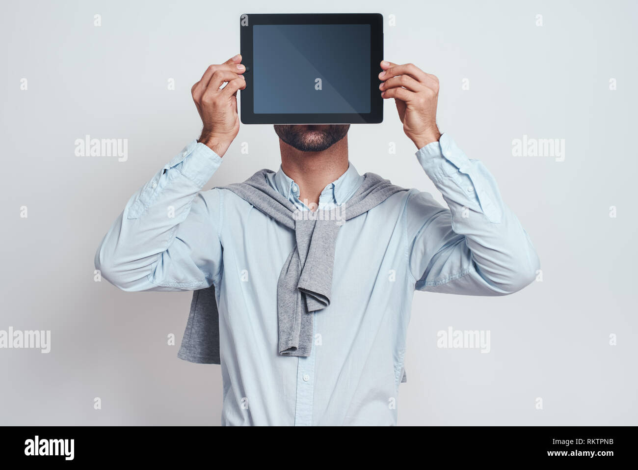 Android. Bearded man in casual wear is holding his digital tablet in ...
