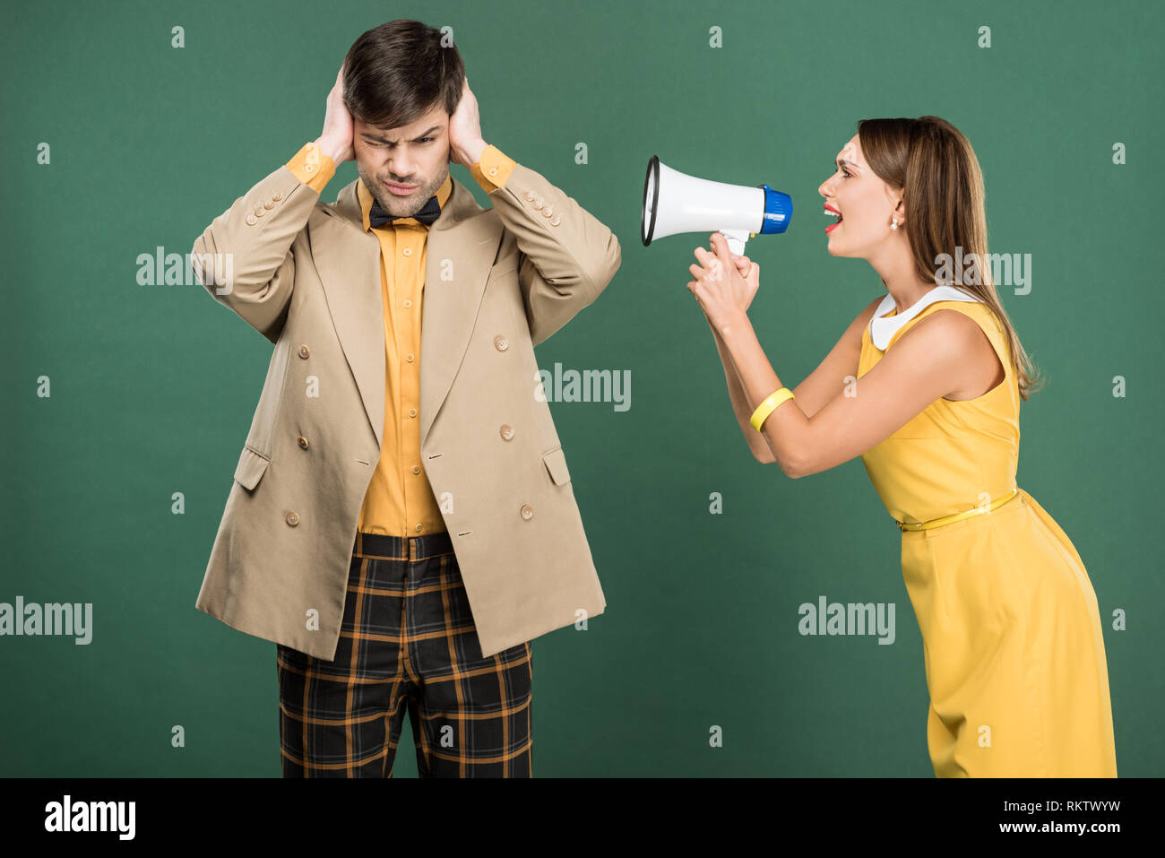 man in vintage clothes covering ears with hands while angry woman ...