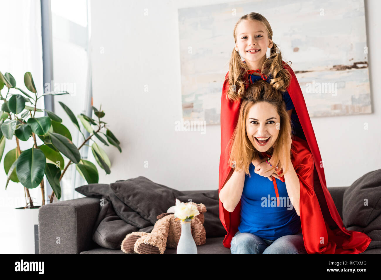 Smiling mother and kid in red cloaks looking at camera Stock Photo - Alamy