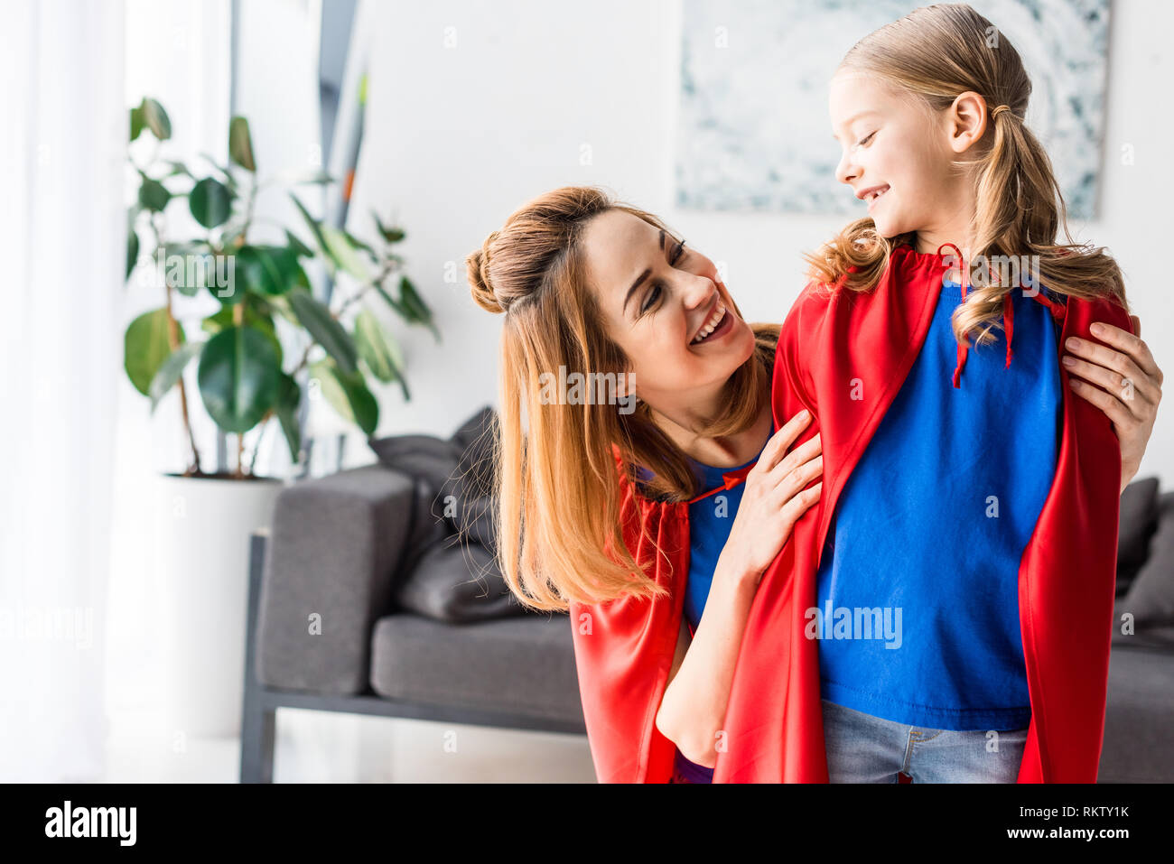 Kid and mother in red cloaks smiling and looking at each other Stock ...