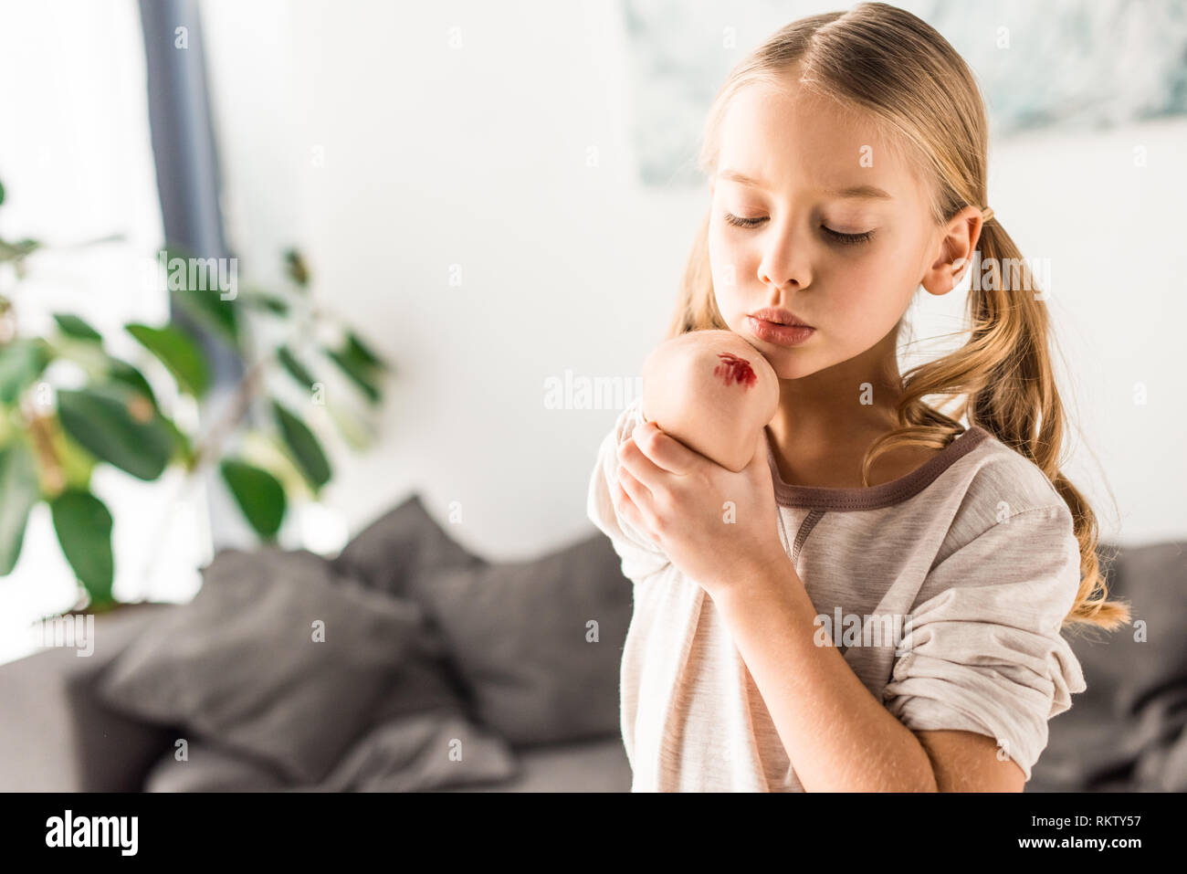 Upset kid blowing on wound at home Stock Photo - Alamy