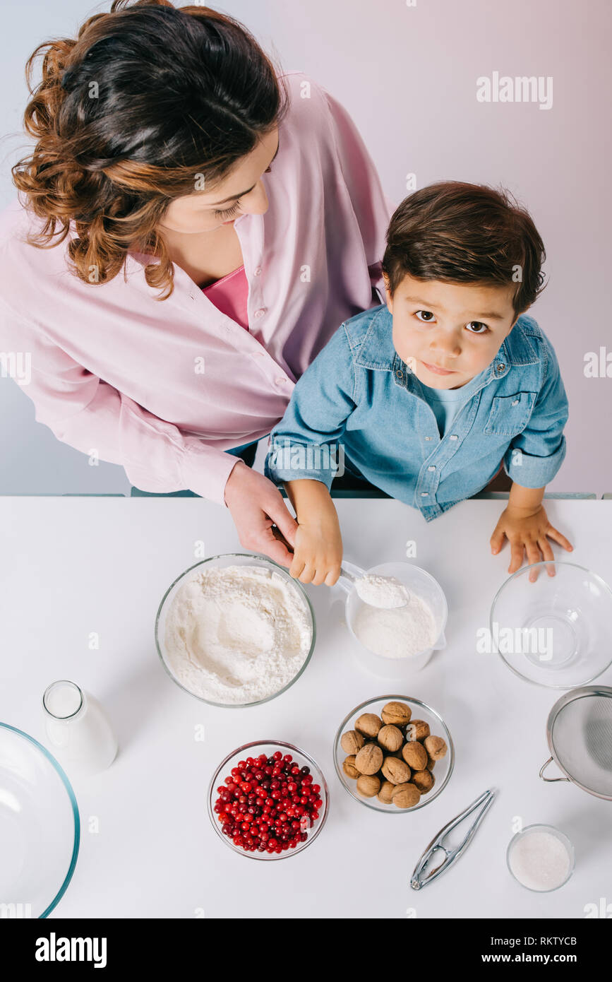 top view of cute little boy and his mom cooking together at white ...