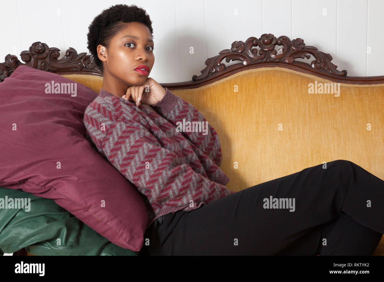 Thoughtful black woman sitting on a couch Stock Photo - Alamy