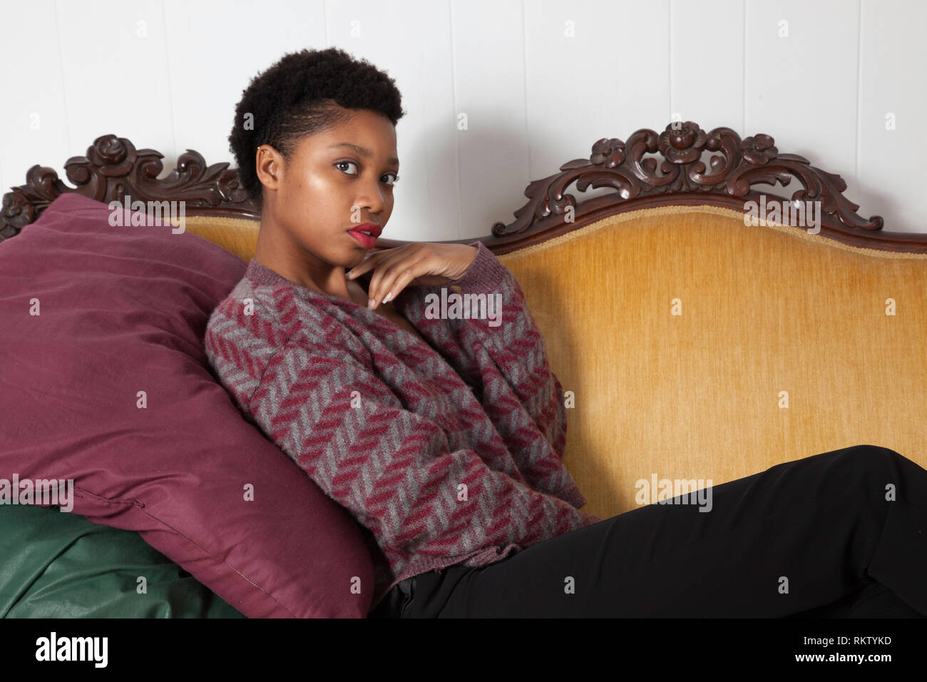 Thoughtful black woman sitting on a couch Stock Photo - Alamy