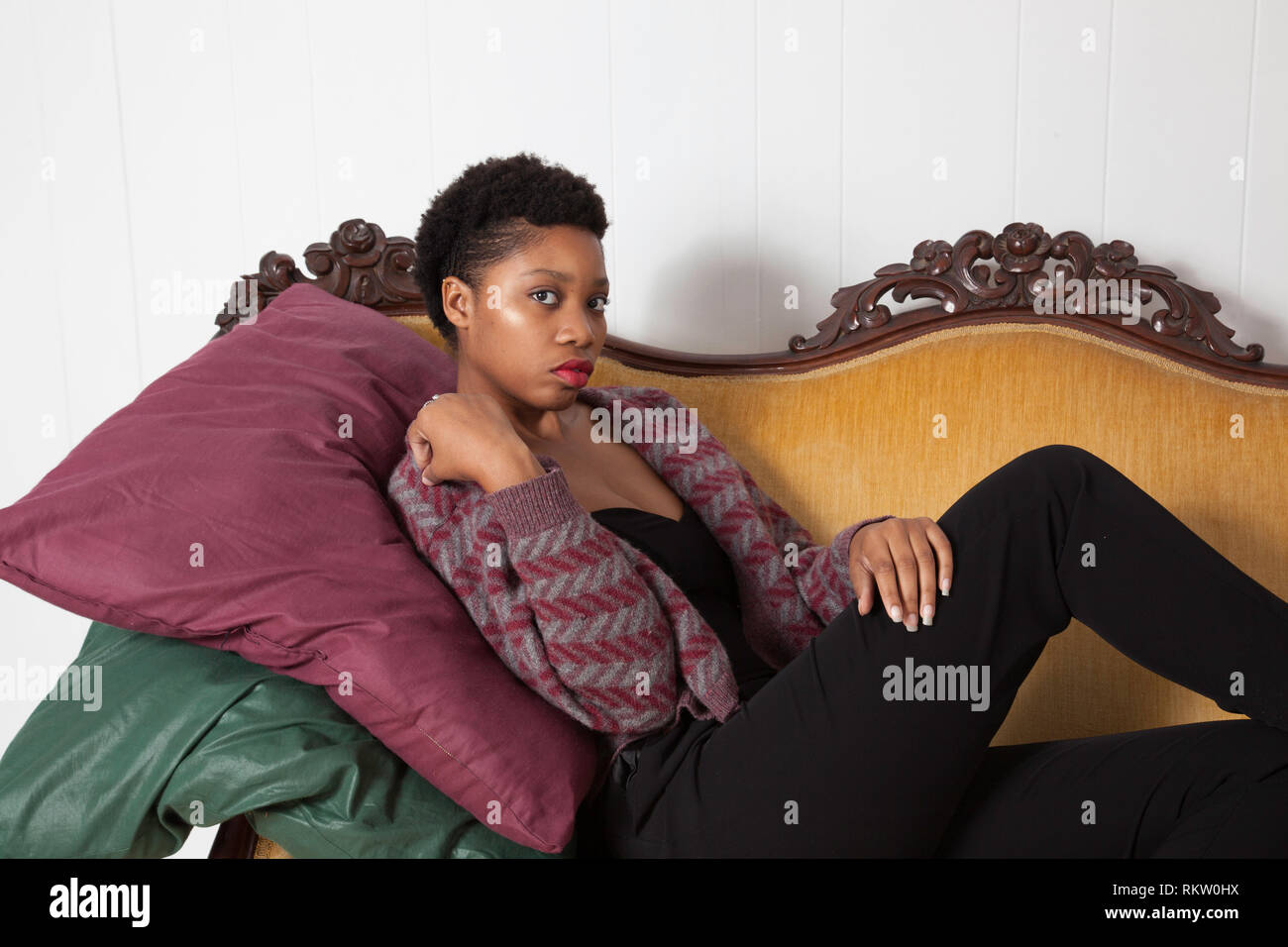 Thoughtful Black woman reclining on a couch Stock Photo - Alamy