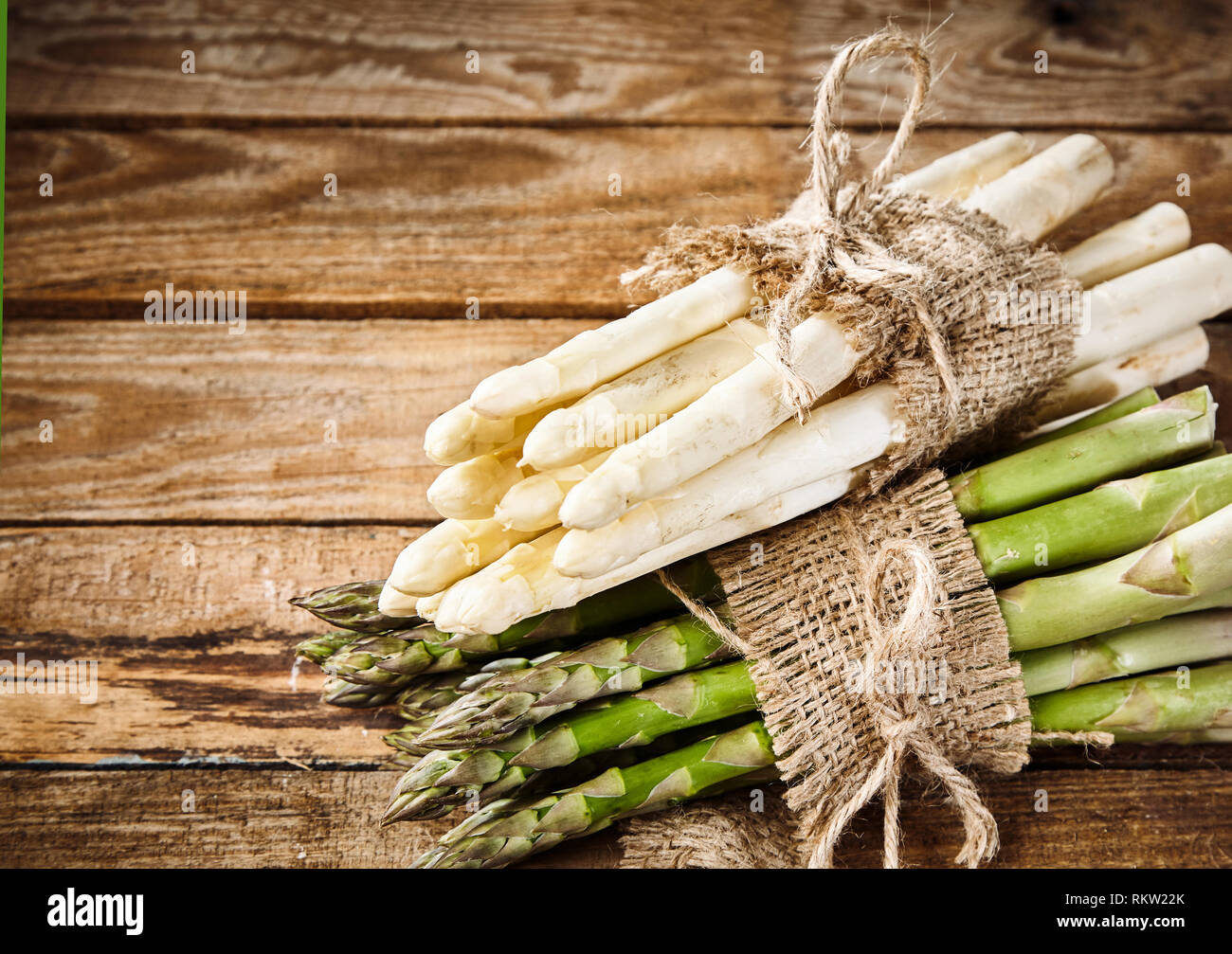 Fresh raw green and white asparagus tips tied in bundles with string ...