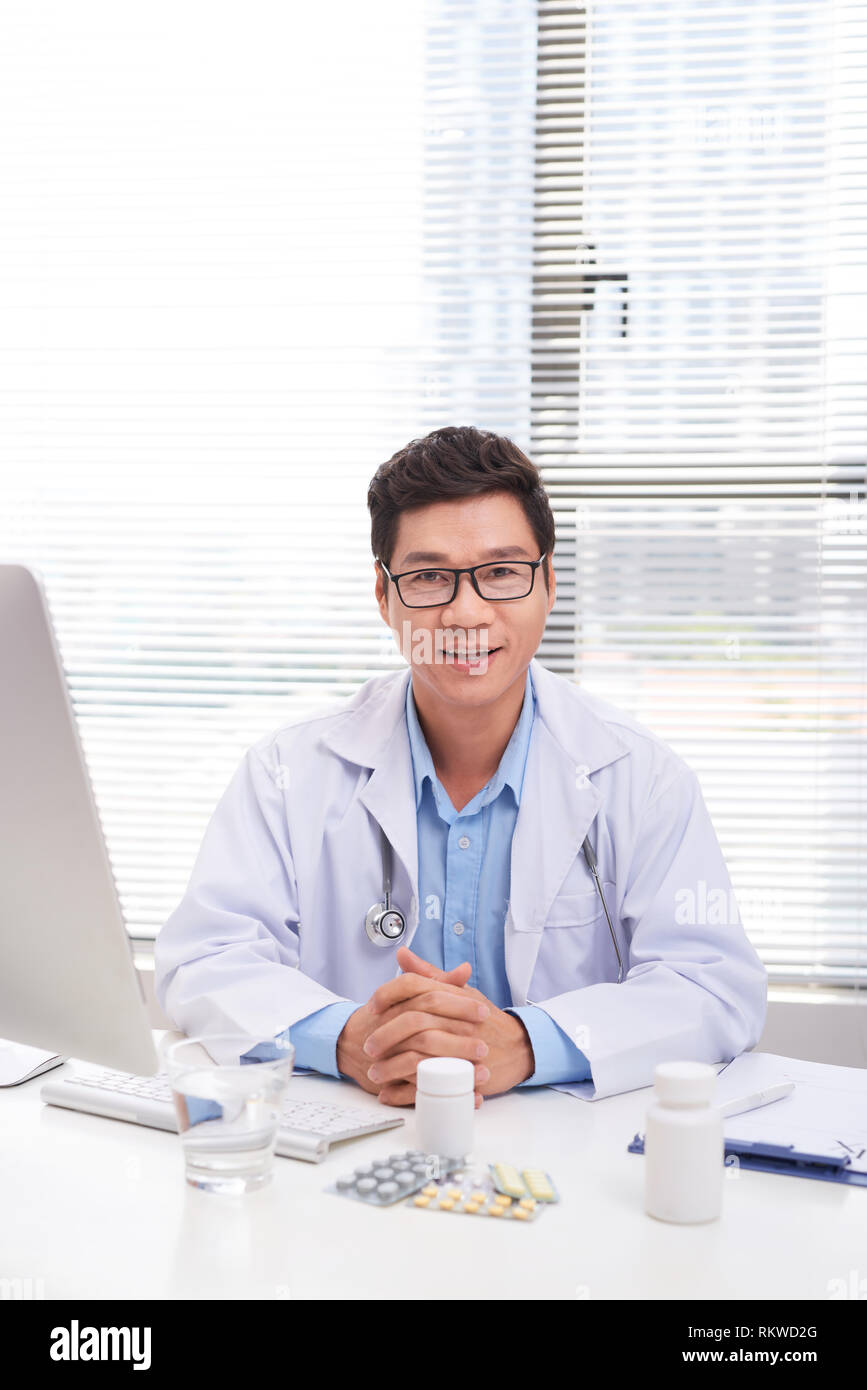 Happy doctor sitting table hi-res stock photography and images - Alamy