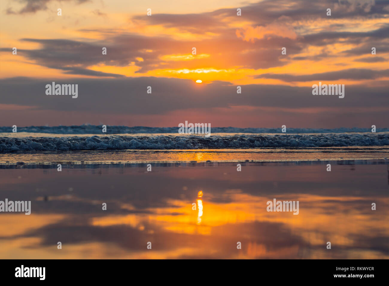 Sunset on the Kuta beach with reflection in the water on the island of ...