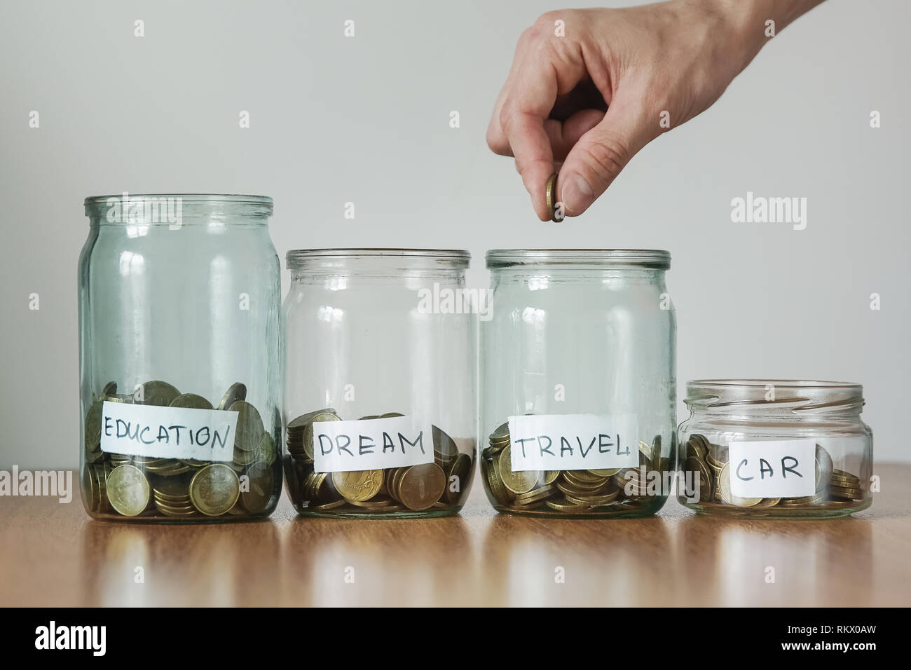 Distribution of cash savings concept. Hand puts coins to the glass ...