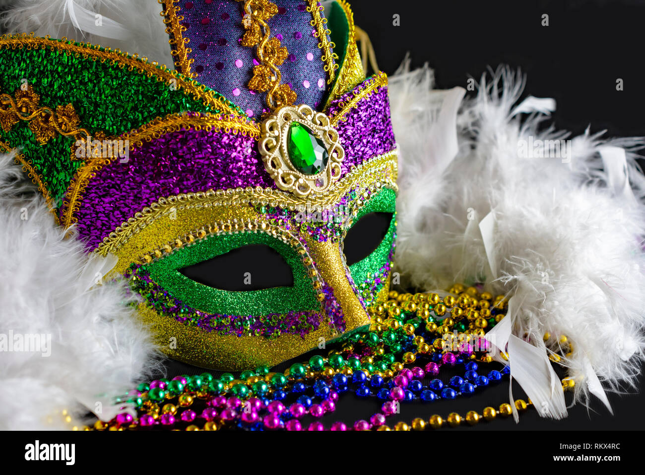 Jester mask with white boa and various colored beads. Side view with a ...