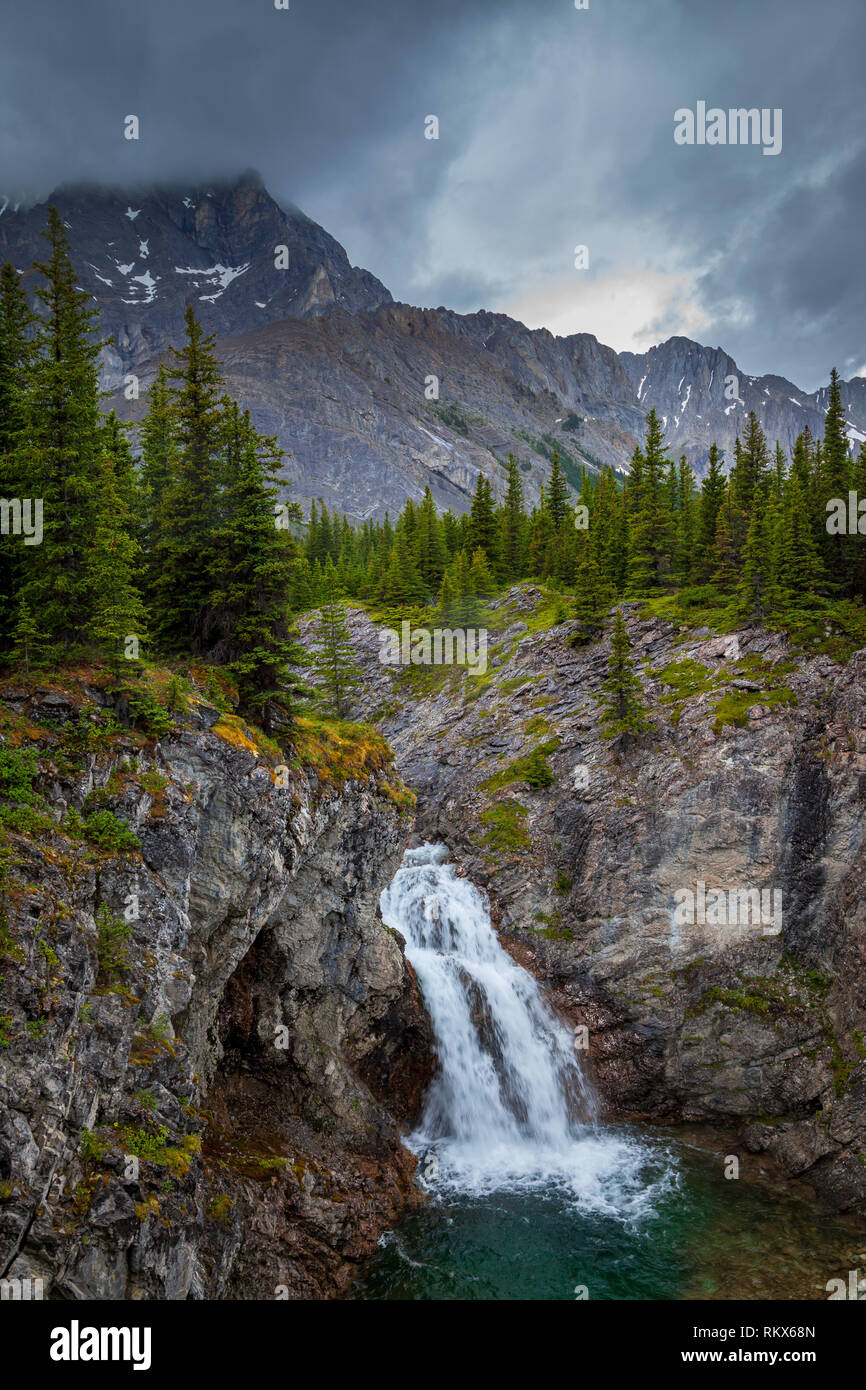 A small waterfall in the Canadian Rocky Mountains on a grey rainy day ...