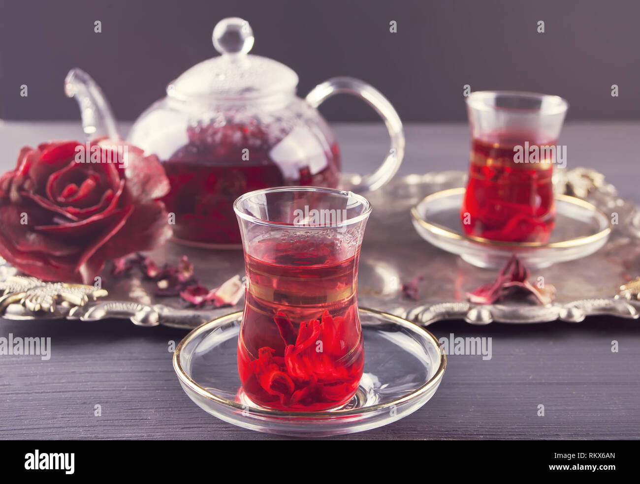 Cups of hot red karkade tea with teapot on the tray on the black table ...