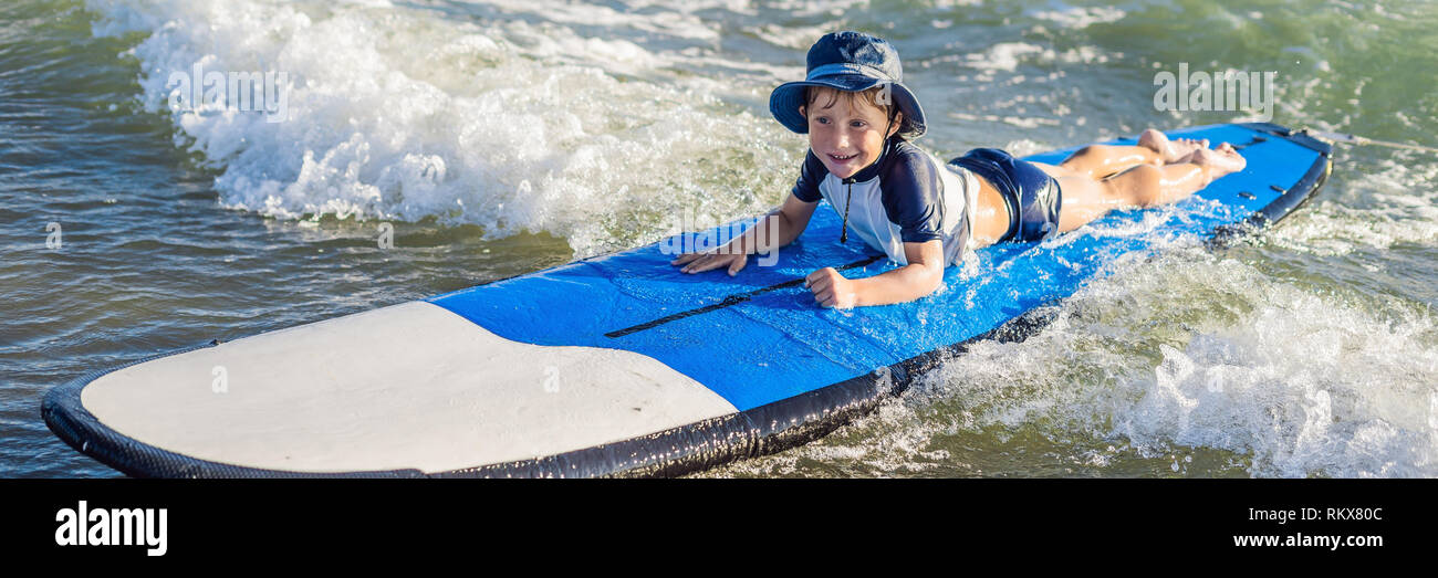 Happy baby boy - young surfer ride on surfboard with fun on sea waves ...