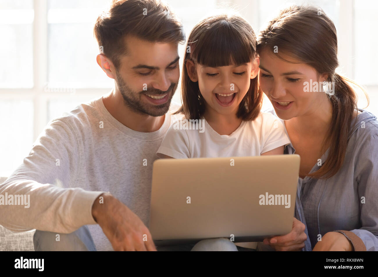 Cheerful mom dad and kid daughter using laptop at home Stock Photo - Alamy