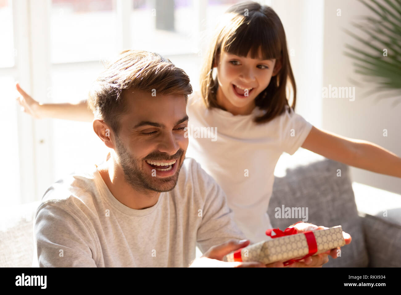 Happy dad laughing receiving gift box from little child daughter Stock ...