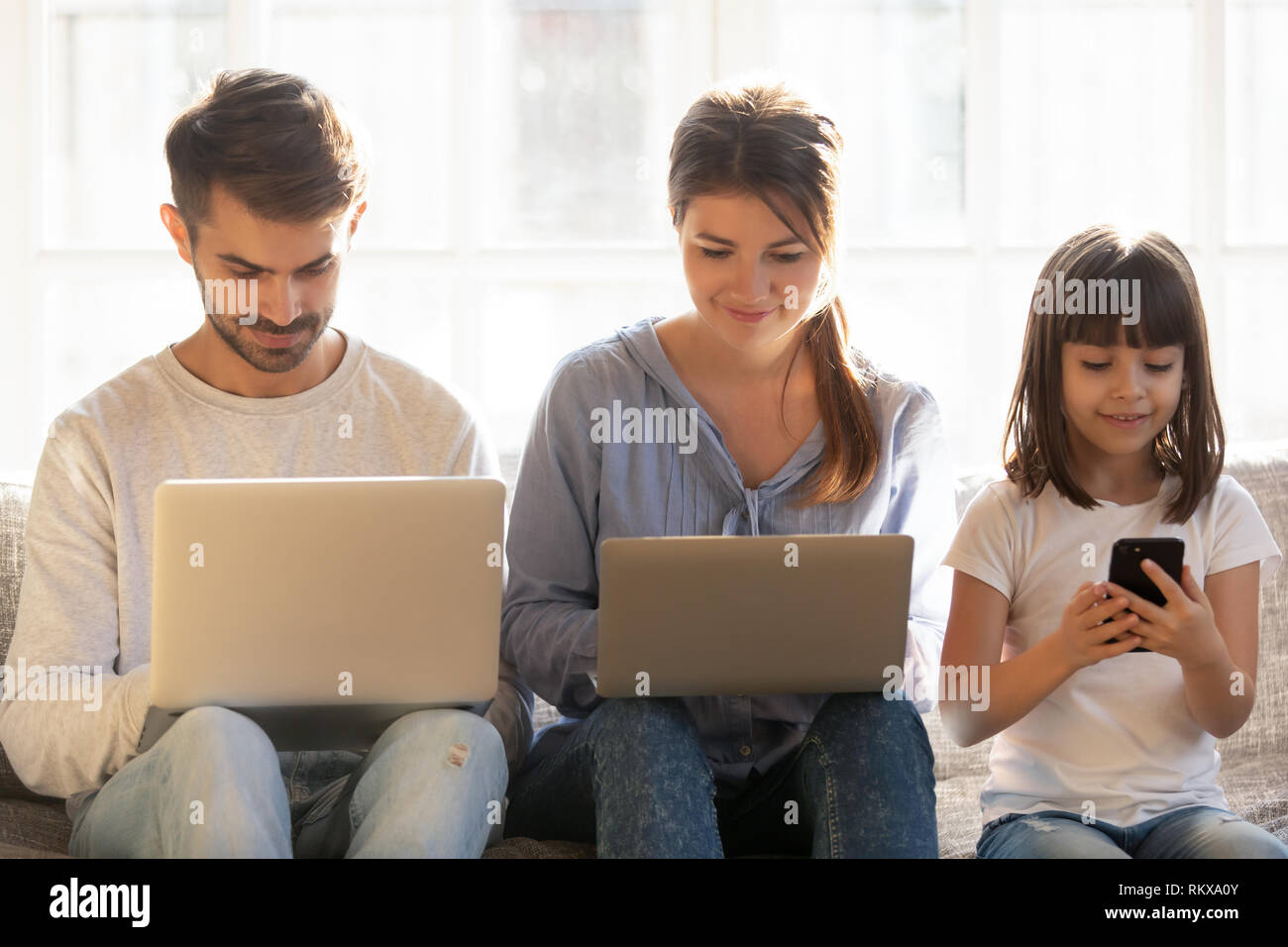 Parents and child daughter using laptops and smartphone at home Stock ...