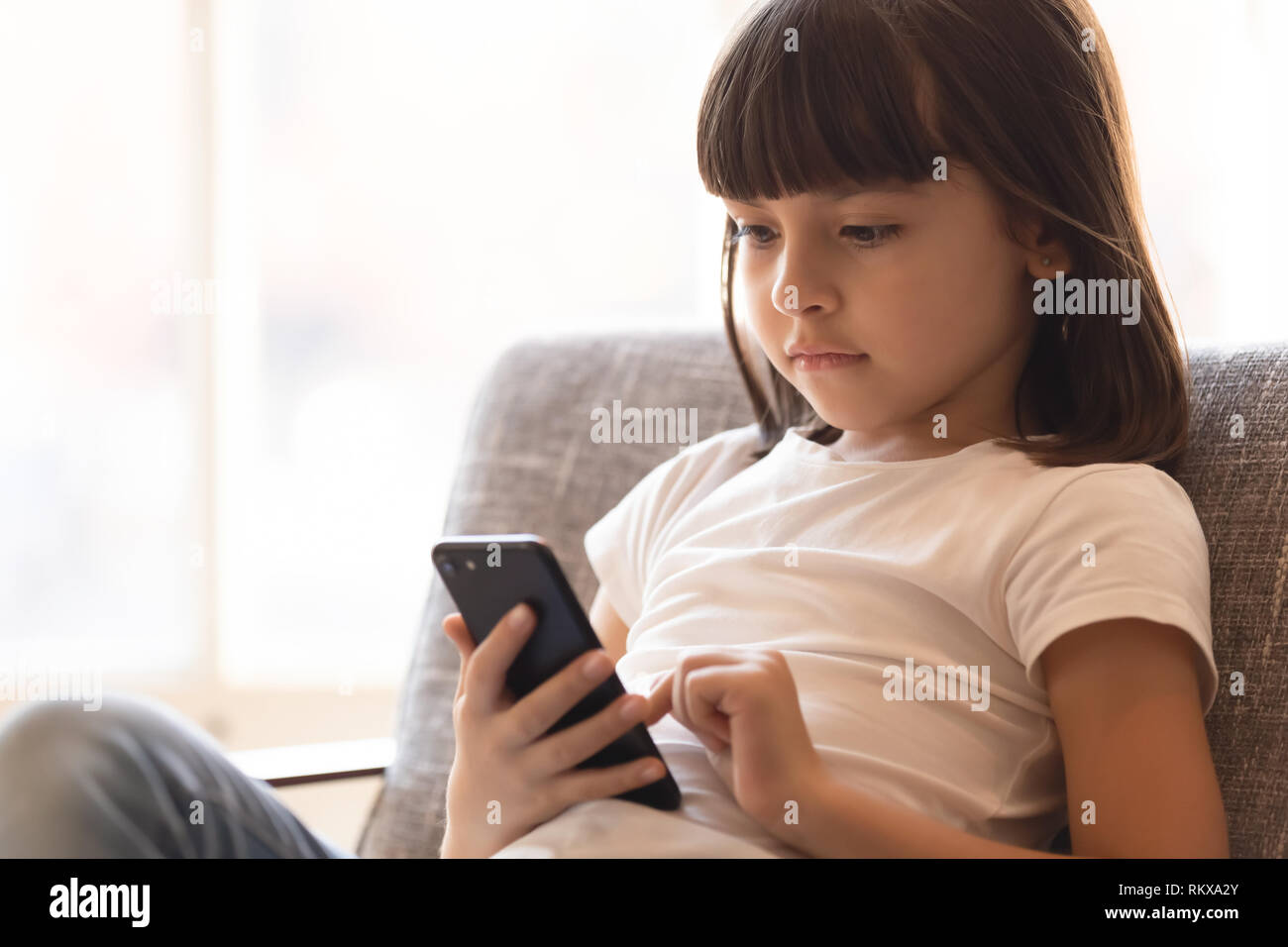 Little smart kid holding smartphone playing game online at home Stock ...