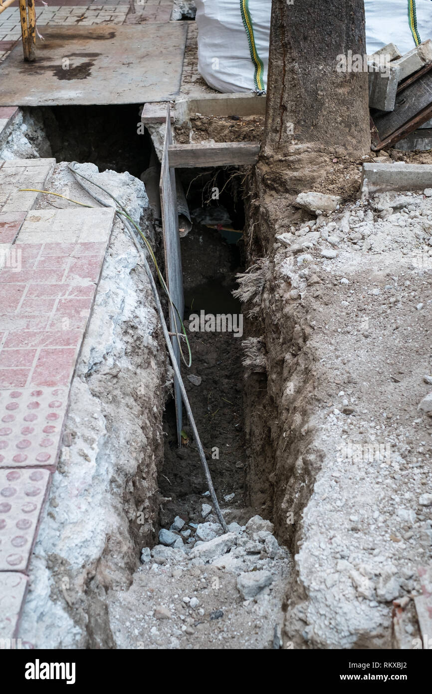 Open trench under pavement with electrical and internet wires Stock ...