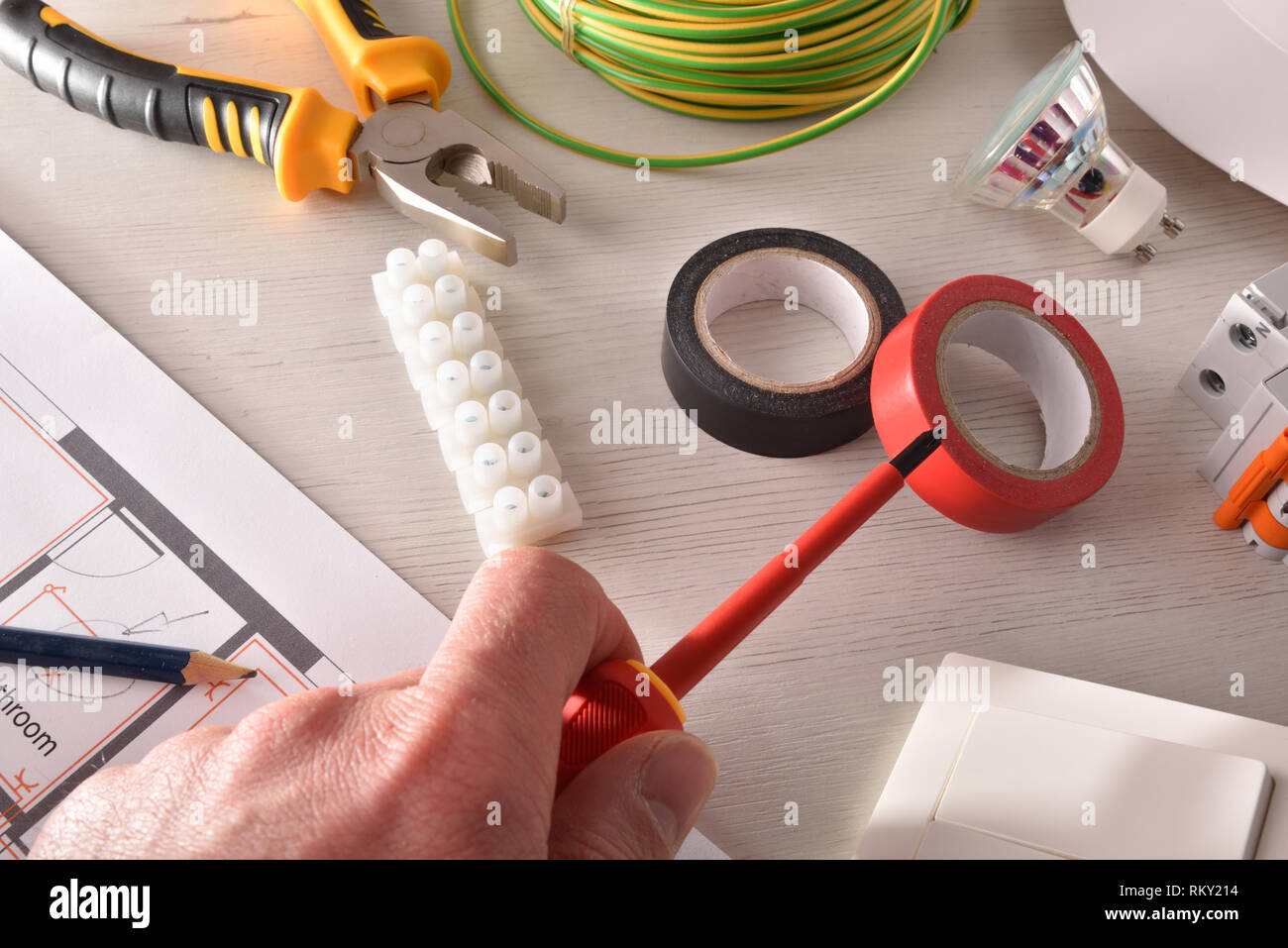 Electrician with screwdriver in his hand on a workbench with tools ...