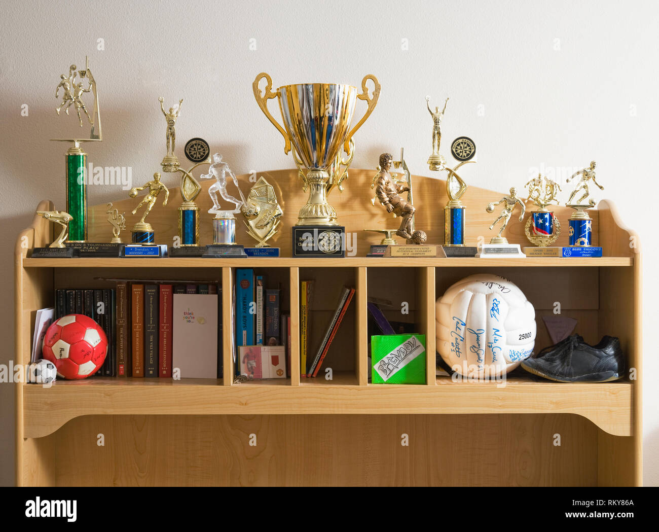 Sports trophies, balls and books on shelves Stock Photo - Alamy