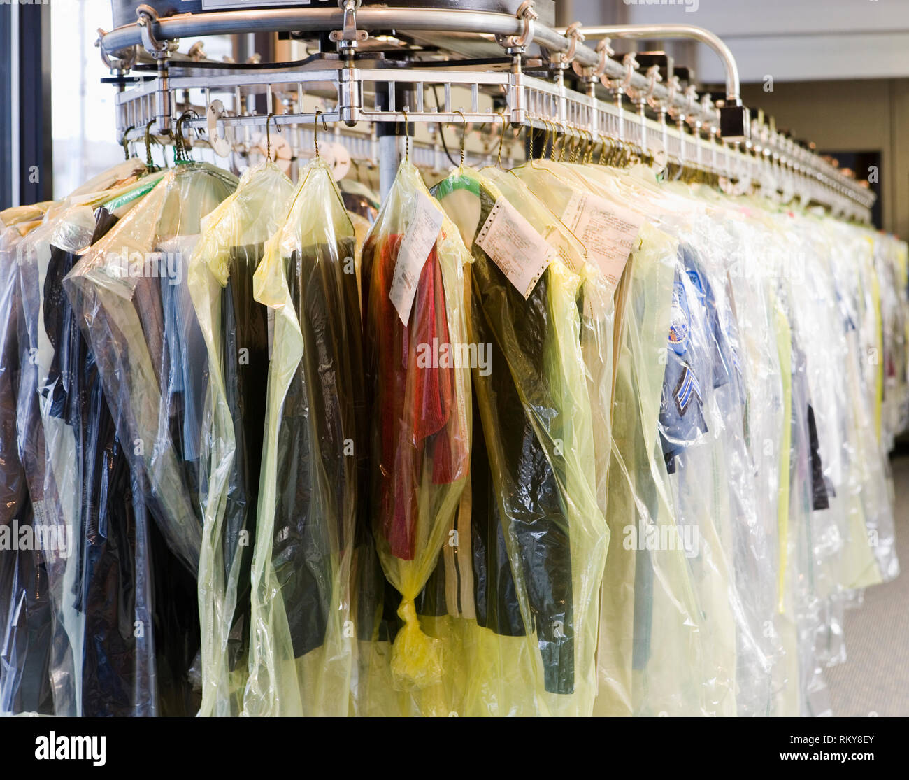 Dry cleaning wrapped in plastic on rack Stock Photo - Alamy