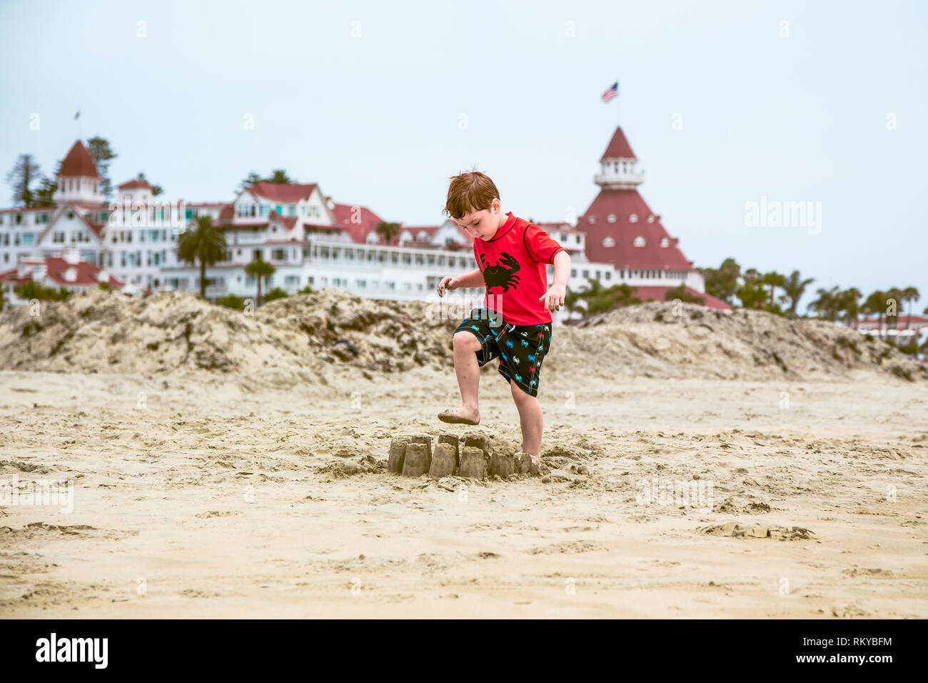 Young boy with red hair stomping on a sand castle on Coronado Beach in ...