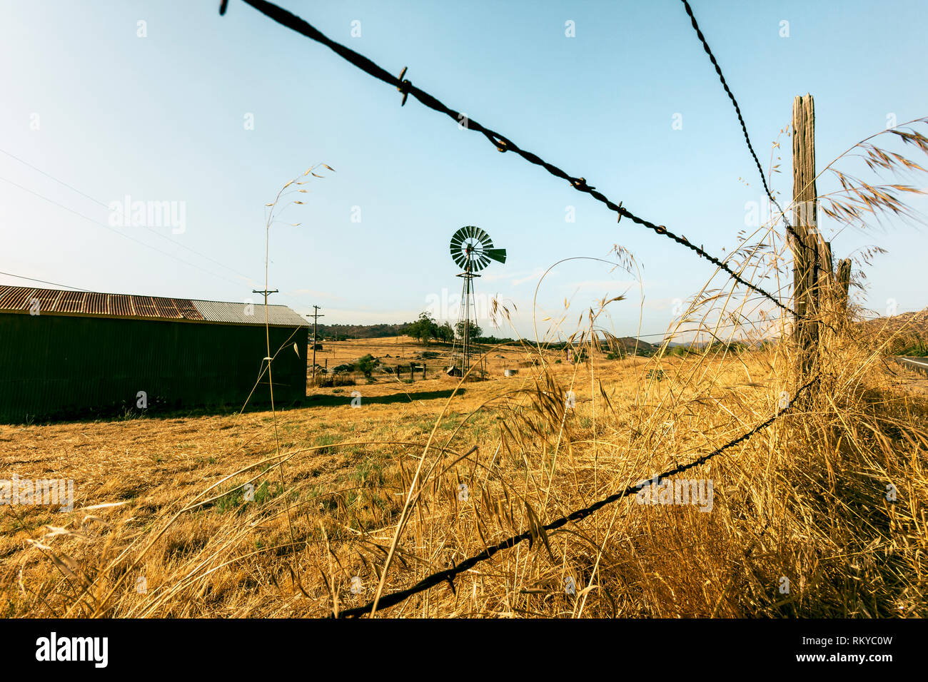 Windmill in a farm field seen through a barbed wire fence Stock Photo ...