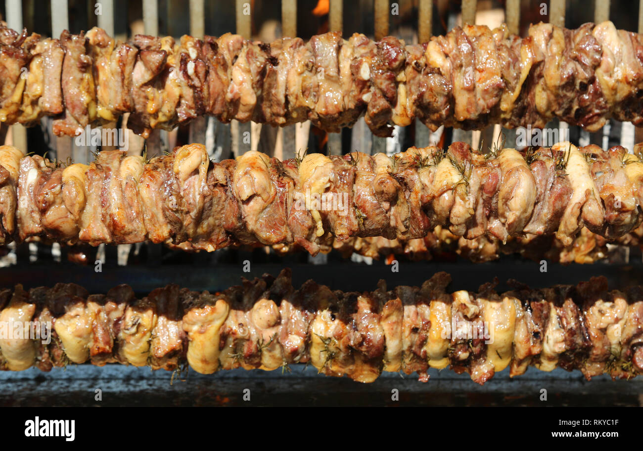spit with chicken meat and pork cooked slowly in the rotisserie at the ...