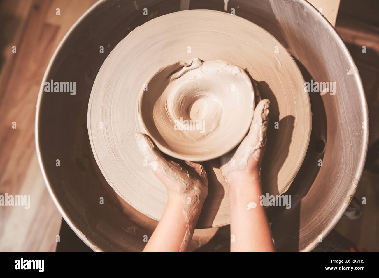 Young potter hands forming ceramic vase with clay on pottery wheel at ...