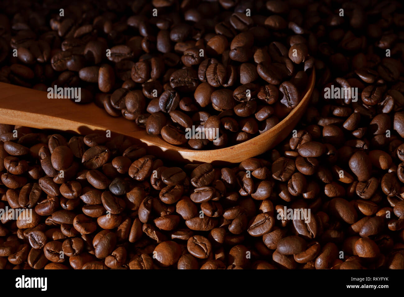 A pile of roasted coffee beans with a wooden ladle Stock Photo - Alamy