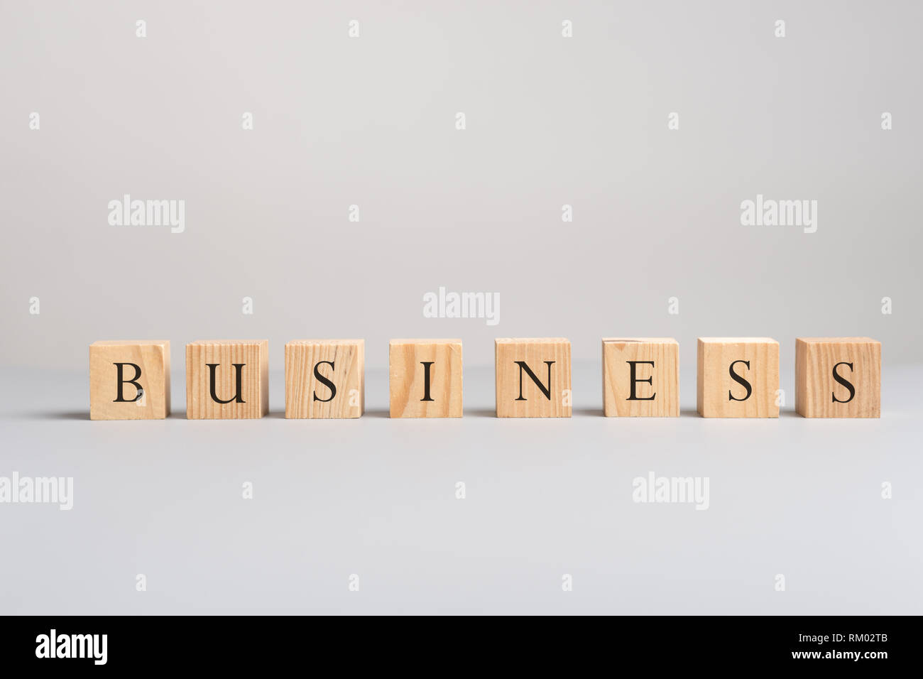Eight wooden blocks with letters spelling BUSINESS over grey background ...