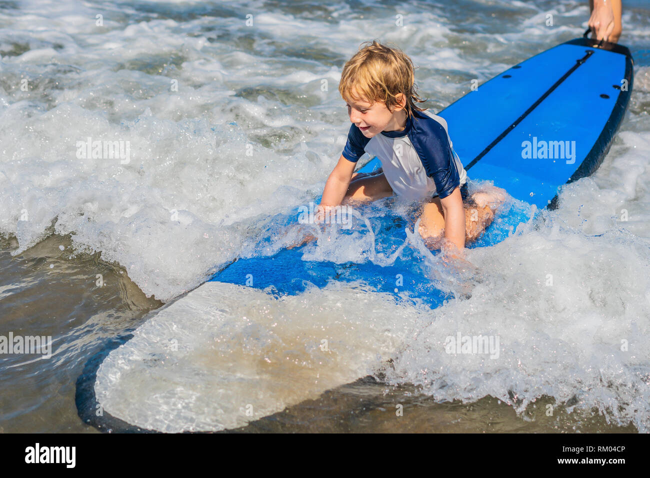 Happy baby boy - young surfer ride on surfboard with fun on sea waves ...