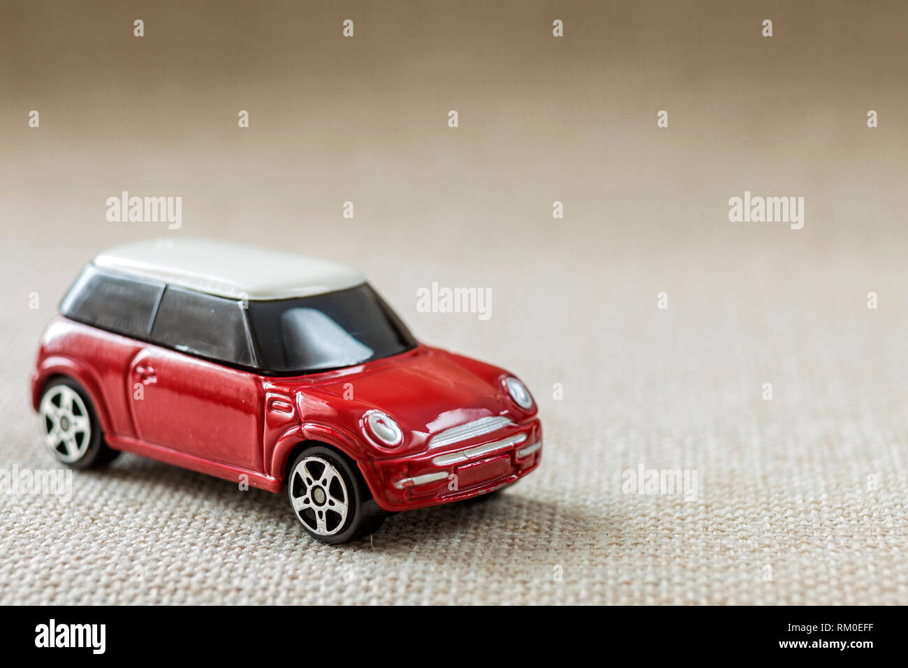 Small bright red metal simple child toy car with dark windows on light ...