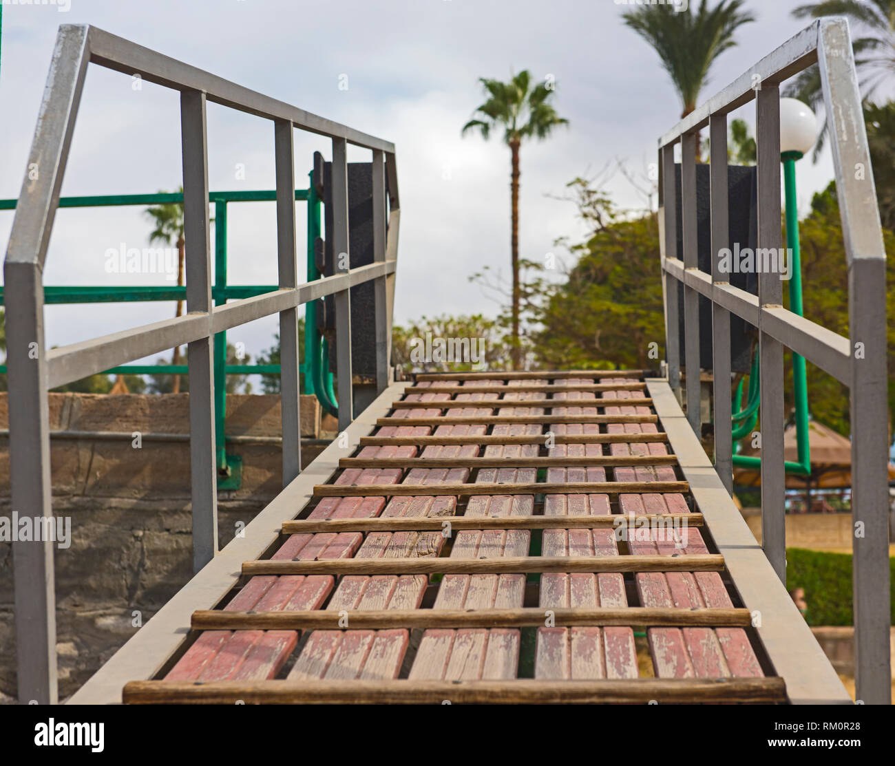 Abstract view of sloping small bridge walkway with metal handrails ...