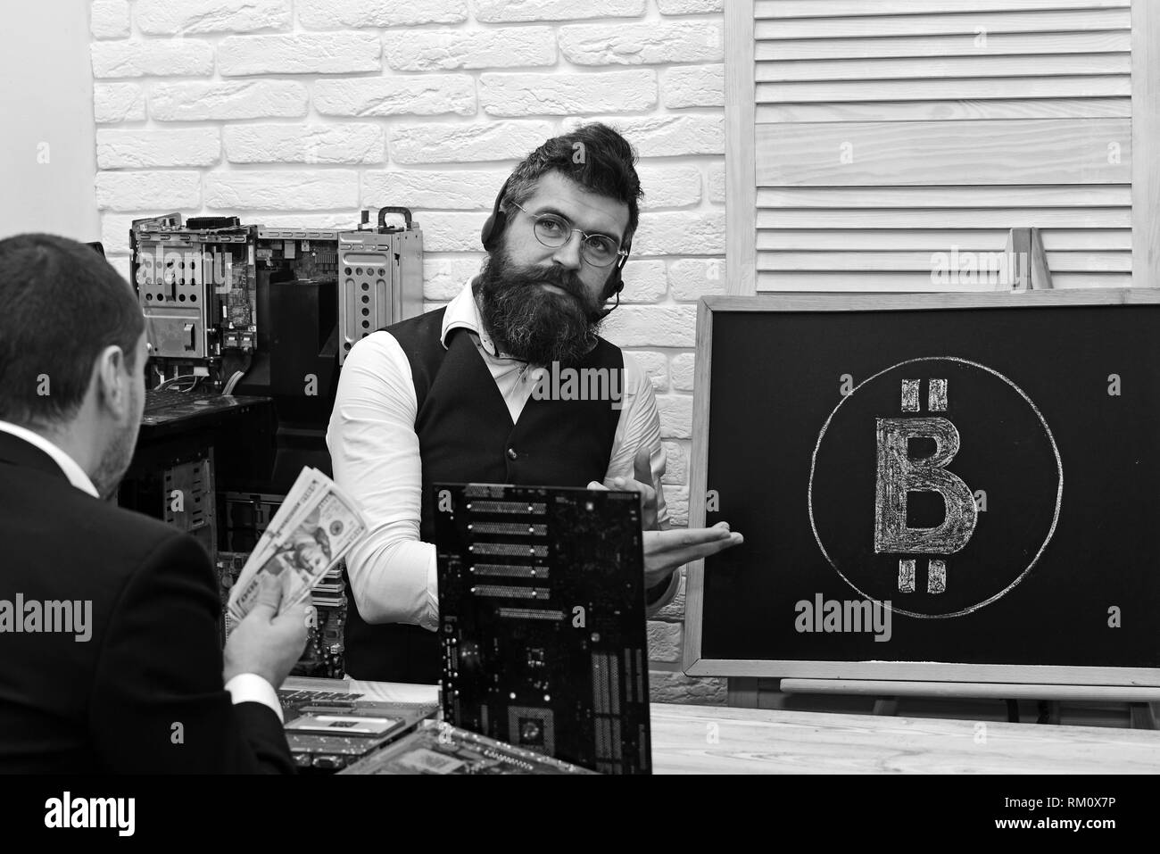 Bitcoin accepted here. Businessmen at office desk. Bearded man point at ...