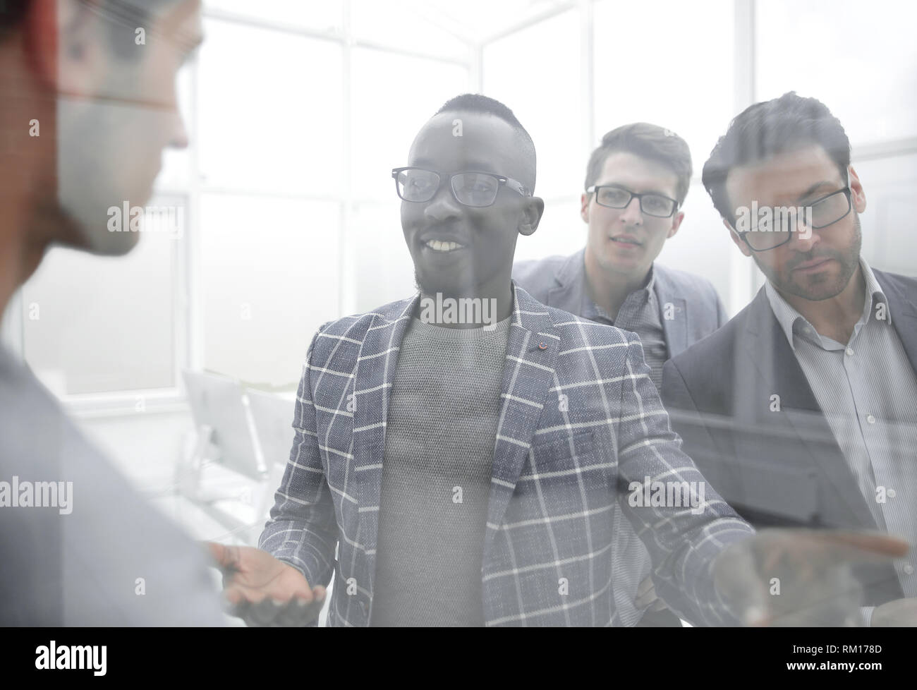 behind the glass. a group of business people talking in the office ...