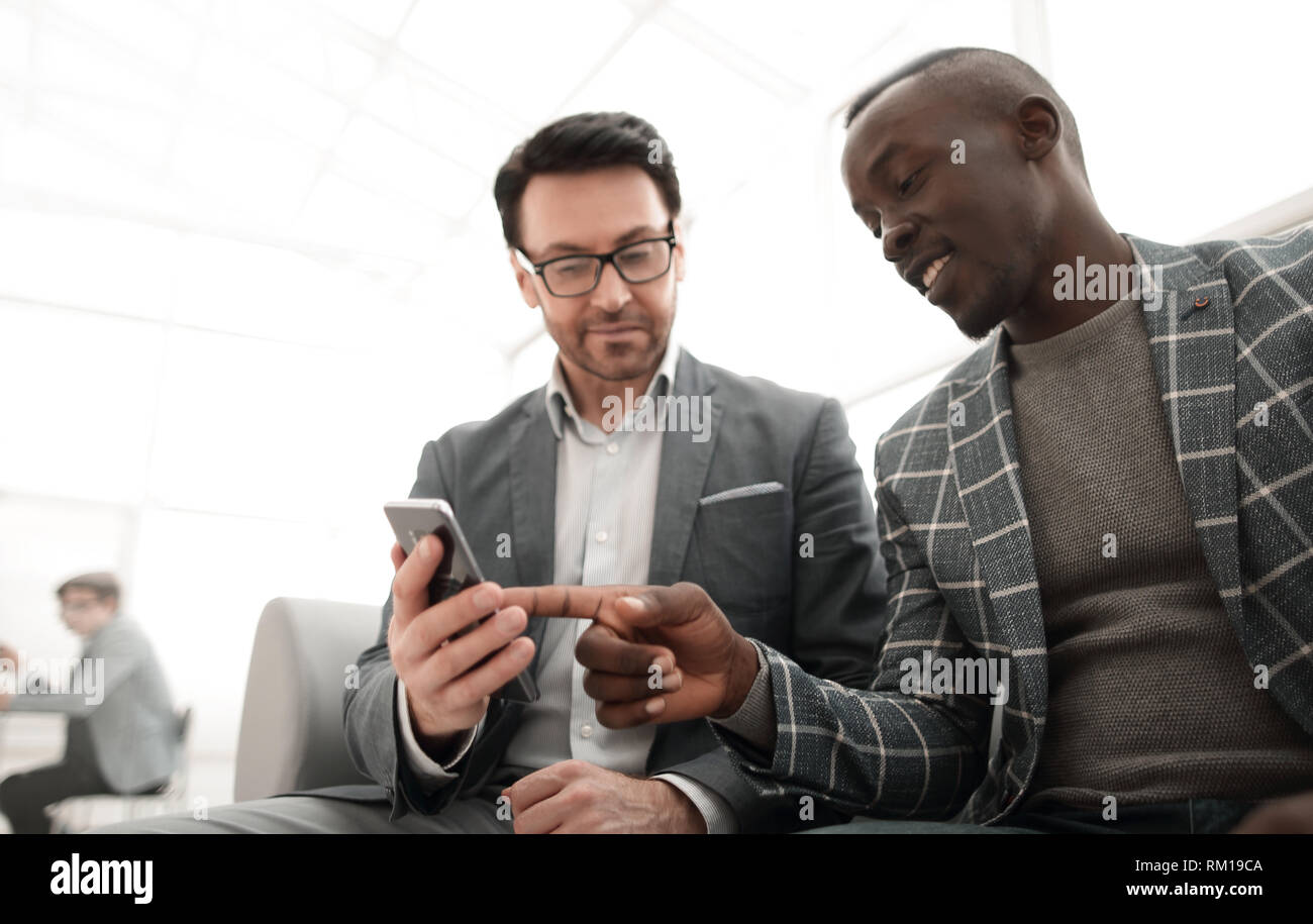 Two business people partners watching media content on a smartphone ...