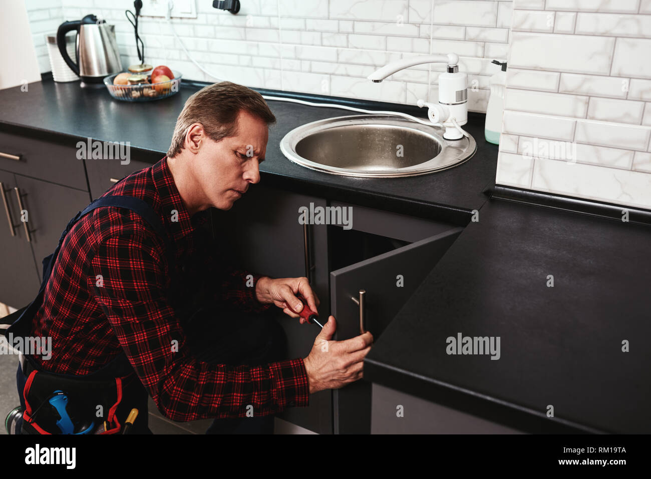 Fixing sink process. Seniour handyman repairing washbasin at the ...