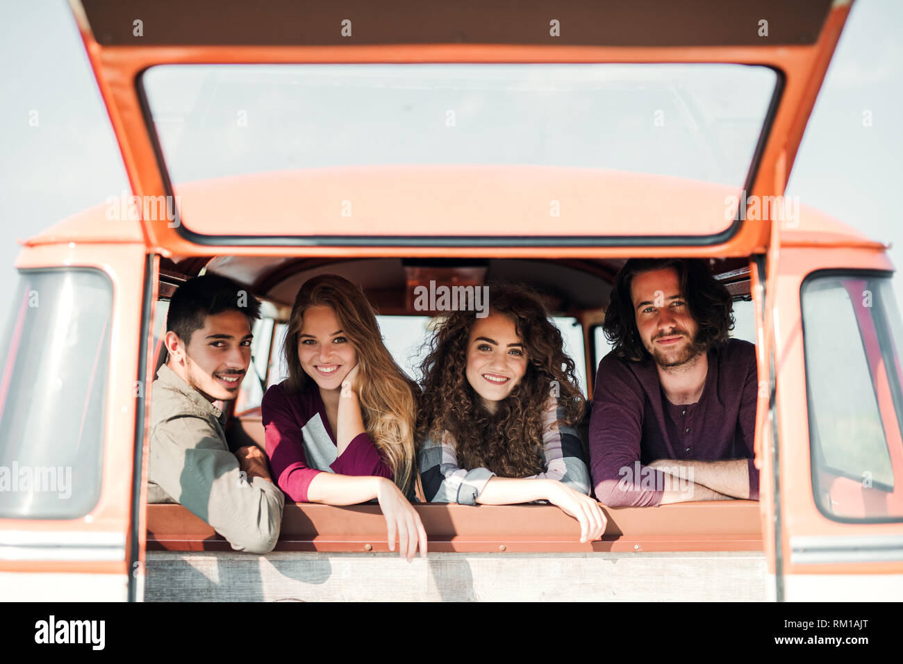 A group of young friends on a roadtrip through countryside, looking out ...