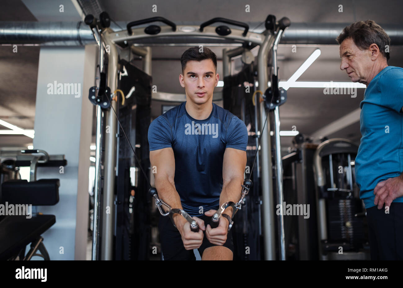 A senior man with a young trainer doing strength workout exercise in ...