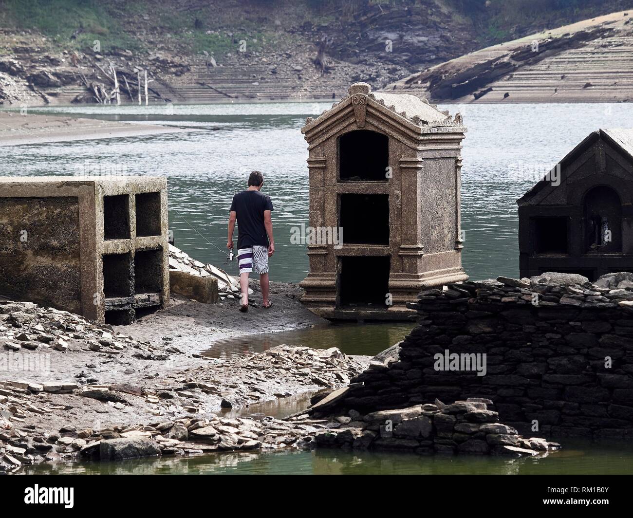 A young fisherman near an old cemetery flooded by the Belesar reservoir ...