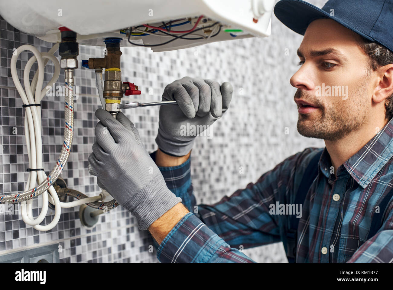 Wrench always with you. Worker set up electric heating boiler at home ...