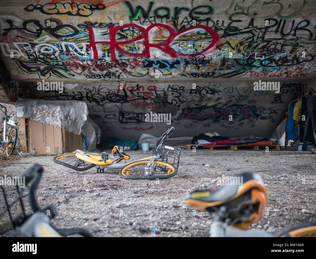Old yellow scrap bicycles under concrete stairs with graffiti and ...