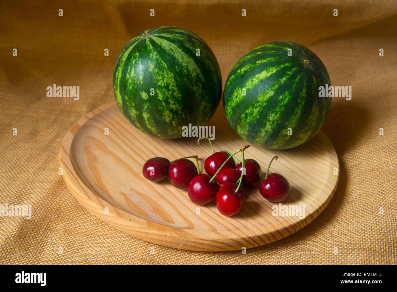 Two watermelons and cherries on wooden dish. Still life Stock Photo - Alamy