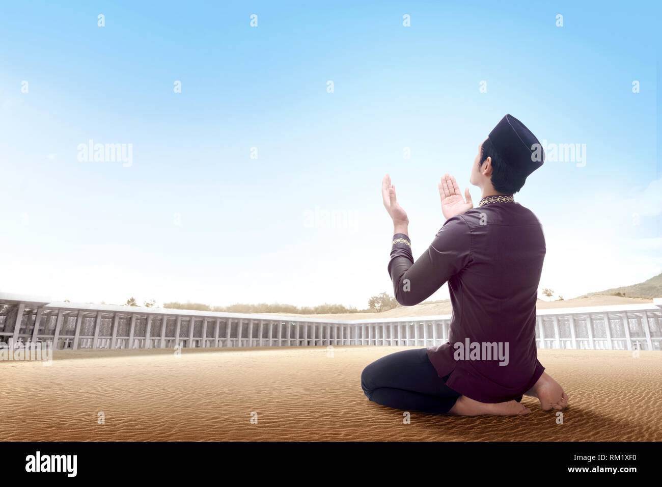 Back view of asian man sitting in praying position on desert raise the ...