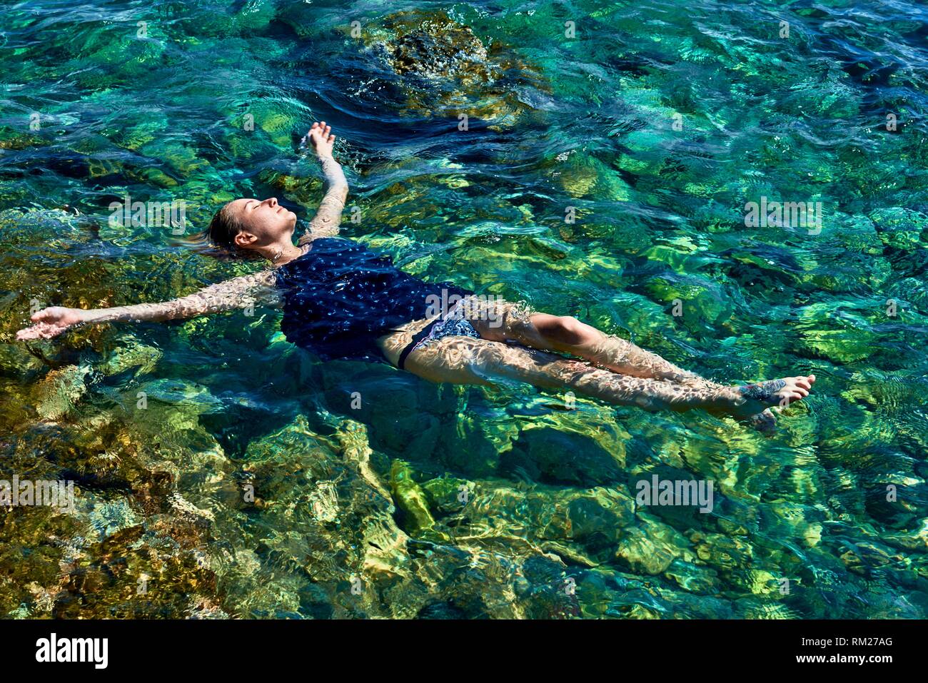 woman floating in sea water, wearing dress and slip, in holiday ...