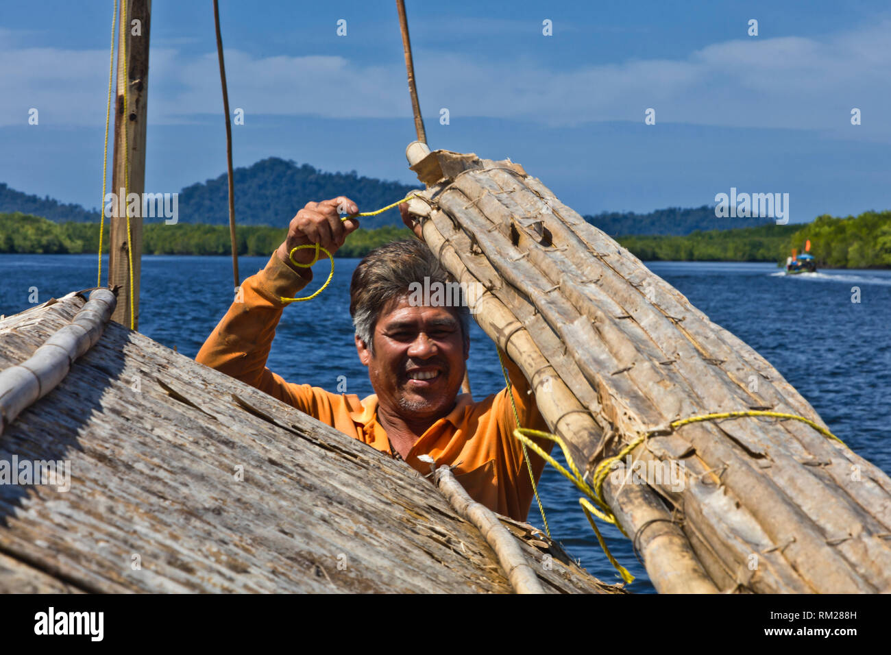 A MOKEN MAN raises his sail on his traditional boat to KHO RA ISLAND in ...
