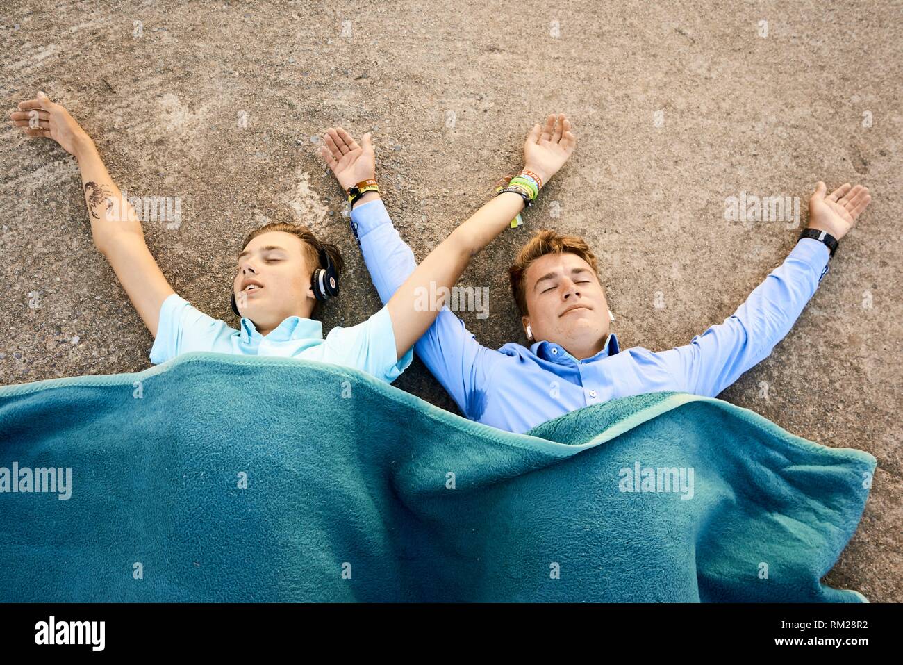 Two young men lying on the floor, under blanket Stock Photo - Alamy