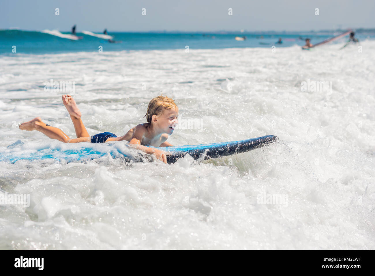 Happy baby boy - young surfer ride on surfboard with fun on sea waves ...